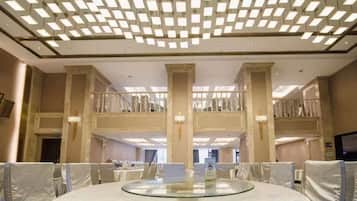 Um hall de hotel com uma mesa redonda, pé direito alto e uma varanda.