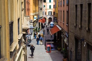 Uma rua estreita com edifícios de ambos os lados, uma cabine telefônica vermelha e pessoas caminhando.