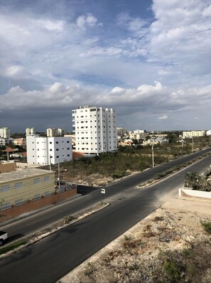 Um edifício de vários andares com telhado plano, rodeado por uma estrada e outros edifícios.