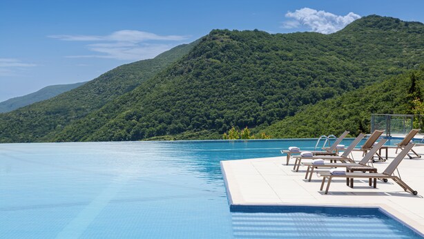 Área de piscina com espreguiçadeiras e vista para uma montanha.