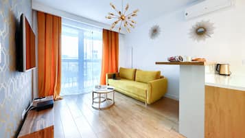Uma sala de estar moderna com um sofá amarelo, uma mesa de centro, uma televisão de tela plana e um aparador de madeira.