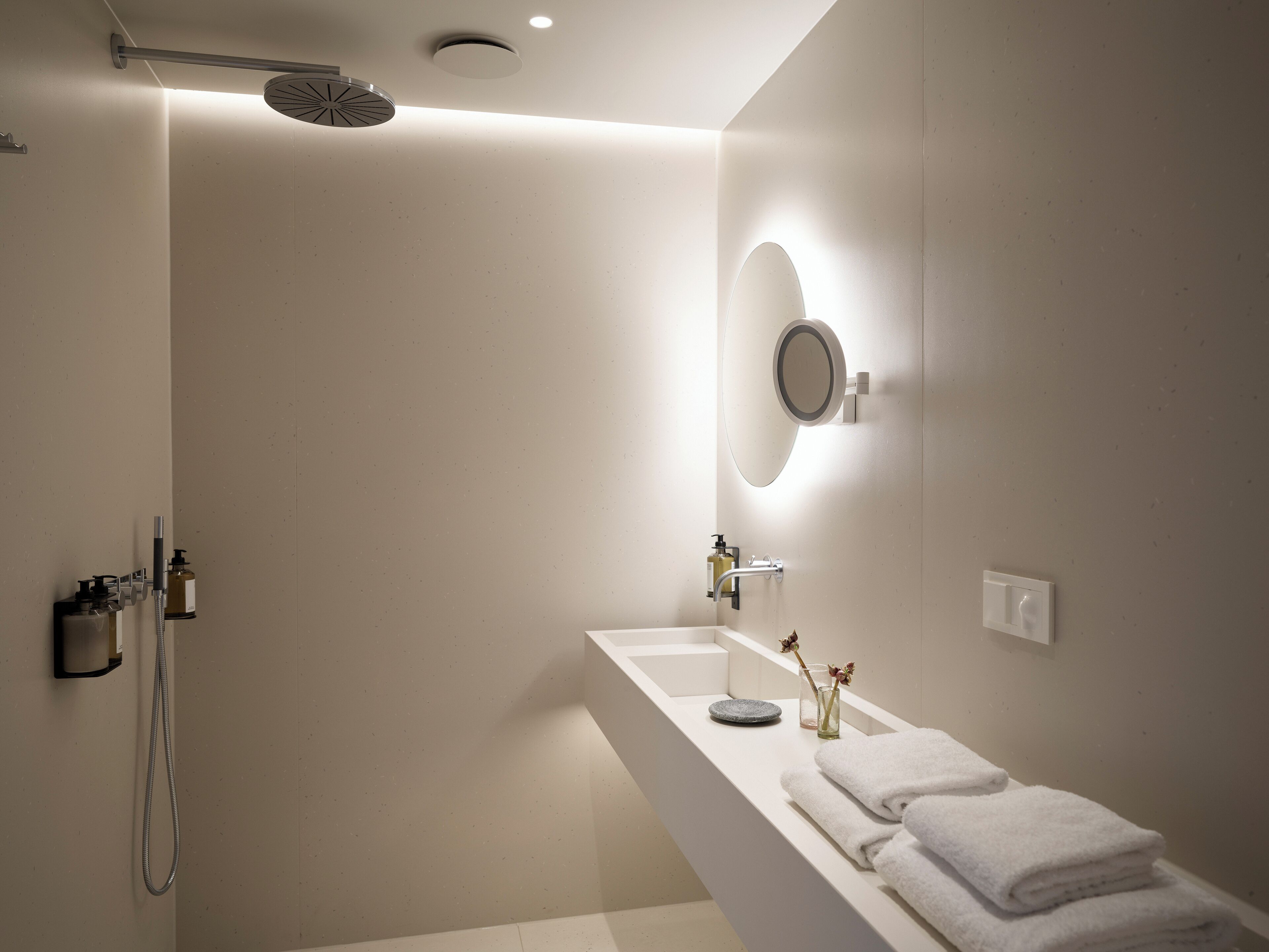 Uma casa de banho moderna com chuveiro, lavatório e espelho.