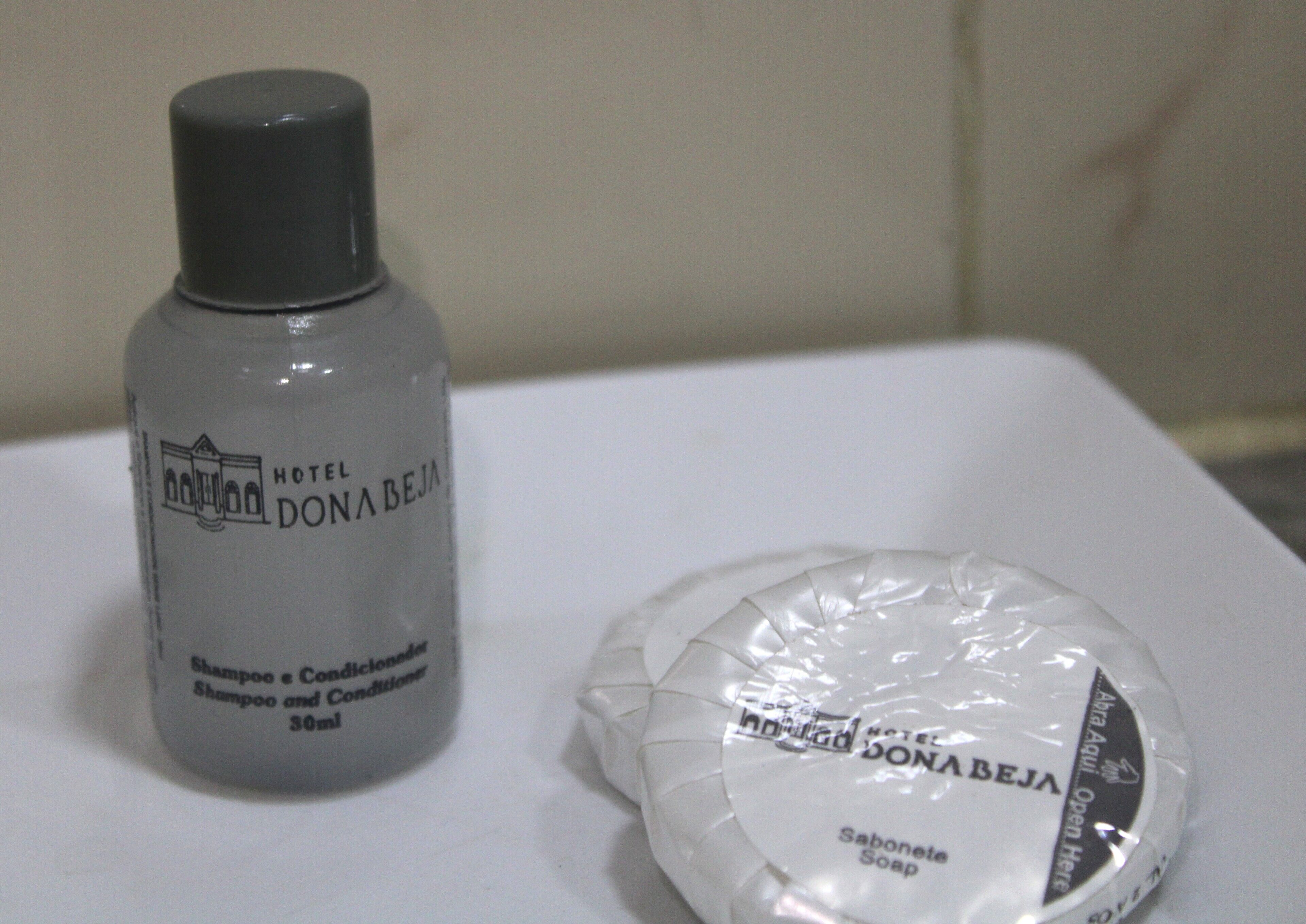 Um frasco de shampoo e condicionador e uma barra de sabonete em uma superfície branca.