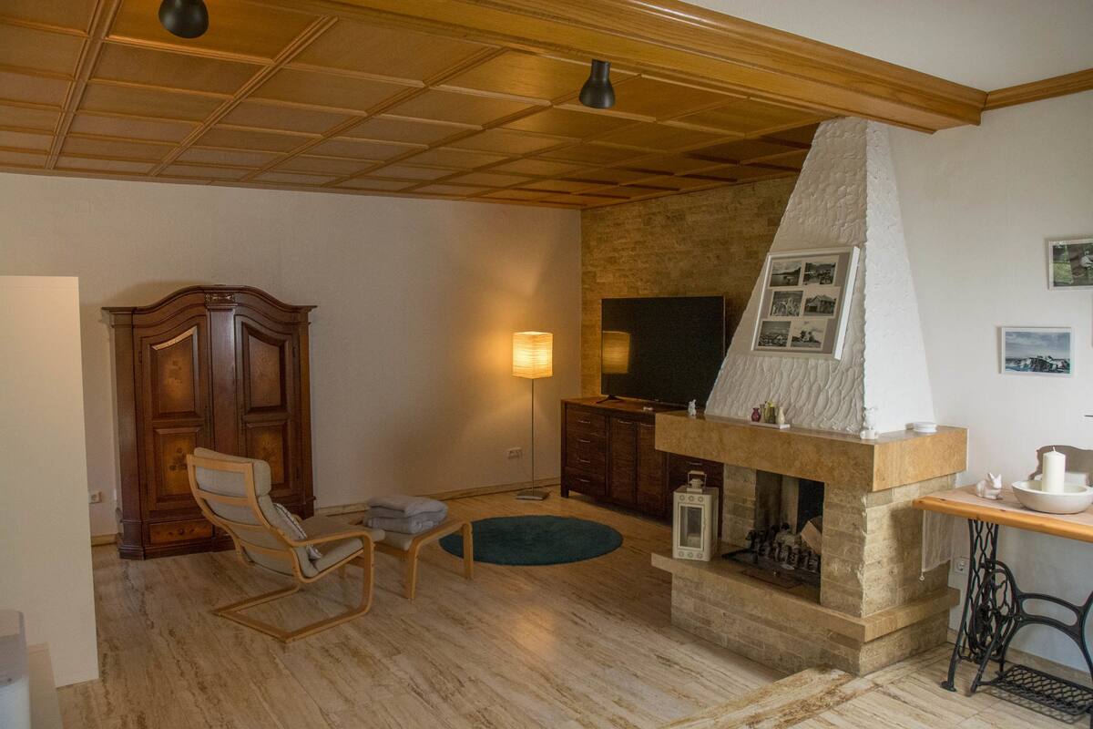 Uma sala de estar com lareira de pedra, móveis de madeira e televisão.