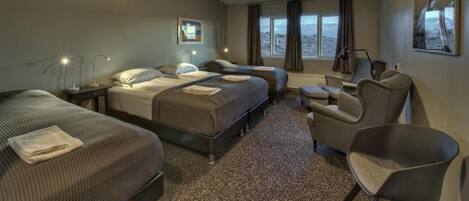 Quarto de hotel com duas camas, uma escrivaninha, uma cadeira e vista para a paisagem.
