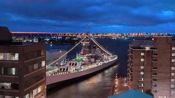 Um navio grande atracado num porto, com um horizonte urbano ao fundo.