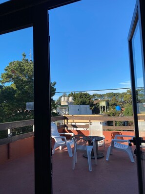 Terraço no telhado com área de estar ao ar livre e vista para prédios e árvores.