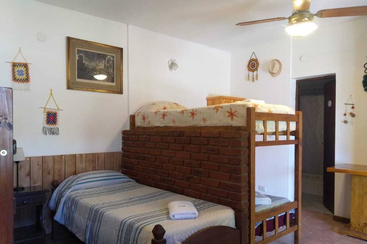 Uma cama de solteiro com cabeceira de madeira, mesa de cabeceira e um ventilador de teto.