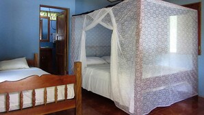 Quarto com cama de dossel, cabeceira de madeira e dossel estampado.