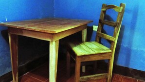 Uma mesa e uma cadeira de madeira num quarto com paredes azuis e chão em mosaico.