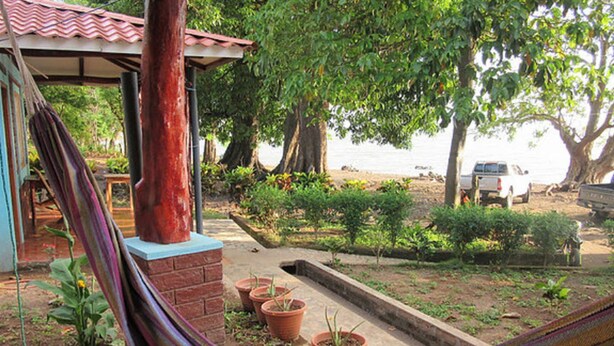 Uma rede com vista para um jardim com plantas em vasos e para uma praia.