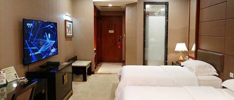 Quarto de hotel com televisão, secretária, duas camas, espelho e porta.