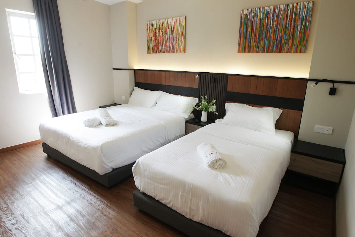 Quarto de hotel com duas camas, piso de madeira e obras de arte nas paredes.