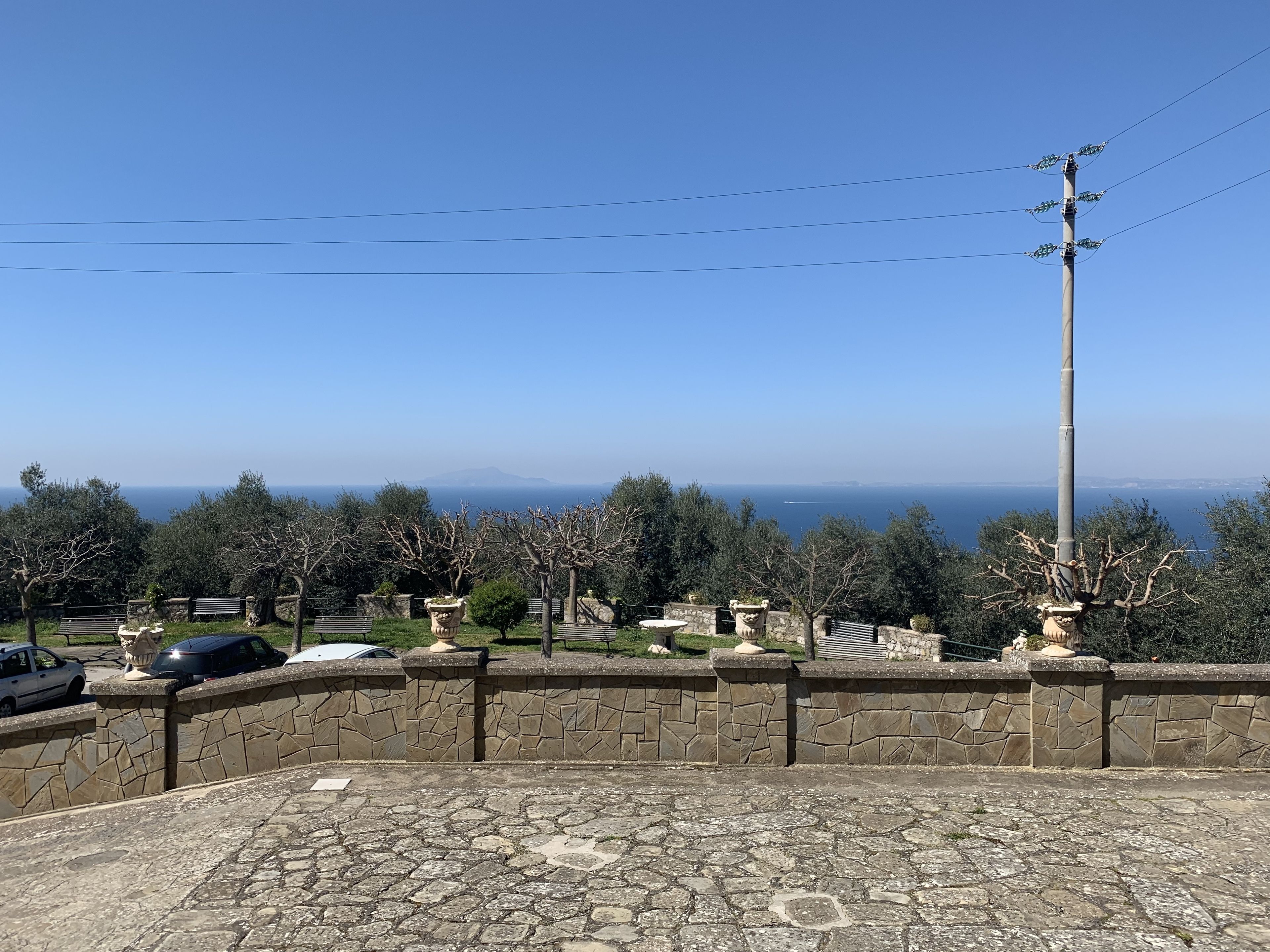 Mural de pedra com vista para o mar e um poste de eletricidade.