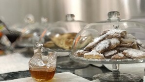 Uma mesa com sobremesas, doces e um pequeno pote de mel.