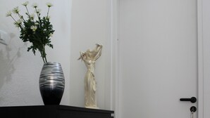 Um quarto com cômoda preta, porta branca e piso estampado.