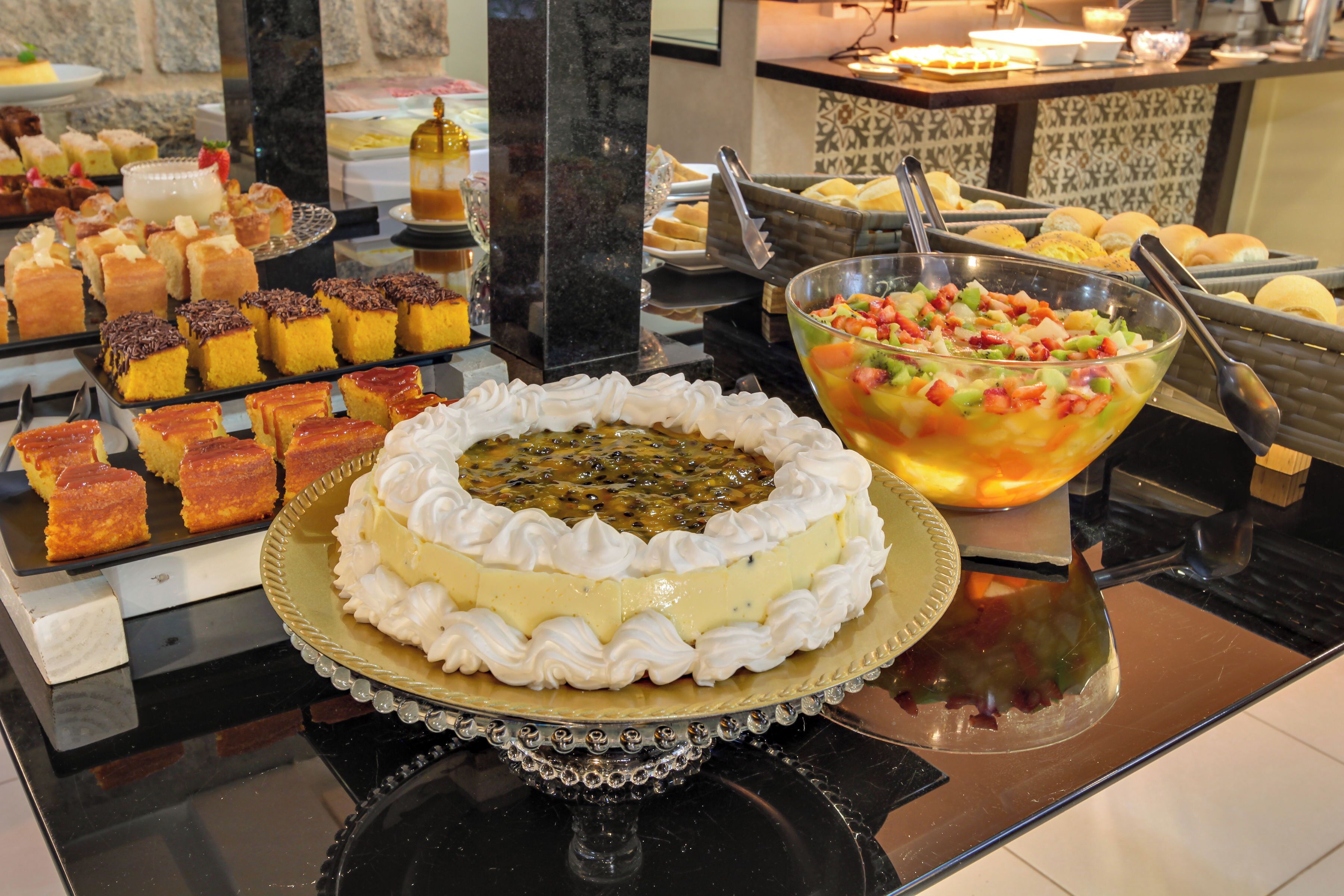 Buffet com diversos doces e salada de frutas.