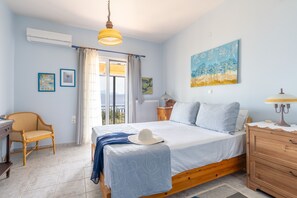 Quarto com cama, escrivaninha, cadeira e janela com cortinas.