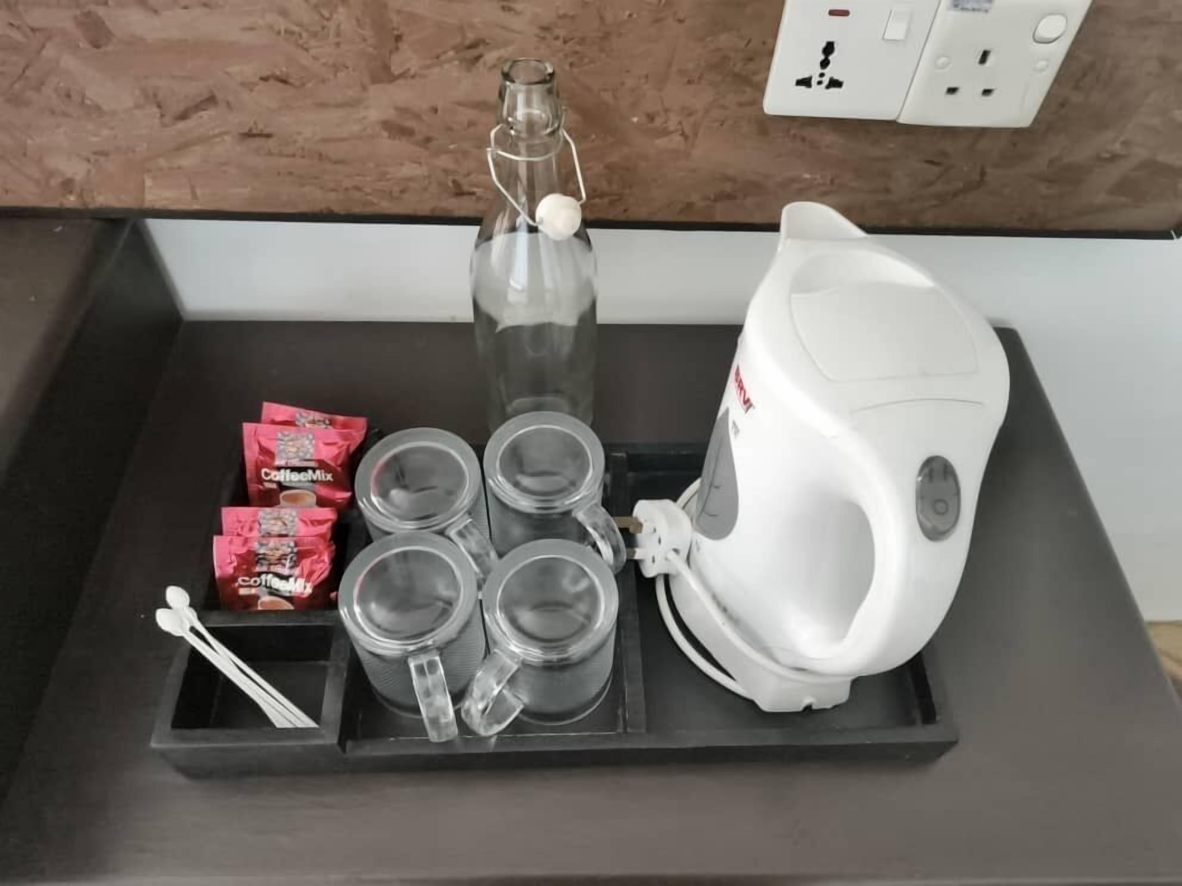 Uma bancada de cozinha com uma cafeteira, uma garrafa, sachês de café solúvel e xícaras medidoras.