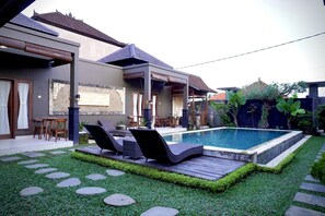 Uma casa moderna com piscina, área de estar ao ar livre e um jardim bem cuidado.