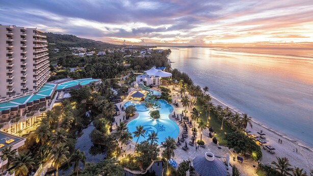 Um resort com várias piscinas, uma praia e um amplo edifício de hotel.