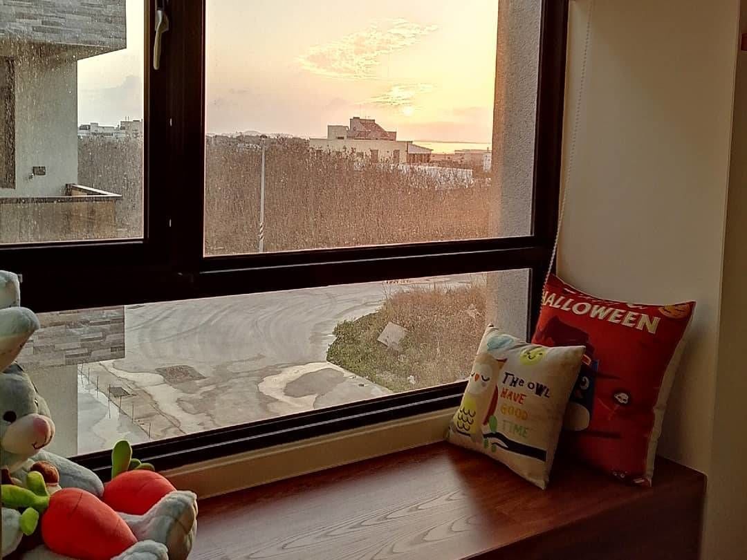 Janela com vista para uma obra, um brinquedo de pelúcia e almofadas com tema de Halloween.