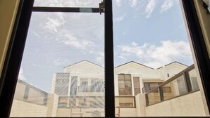 Vista pela janela, com chão de madeira, mostrando um conjunto de edifícios.