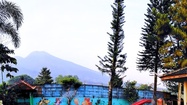 Piscina com um mural, um escorregador e montanhas ao fundo.