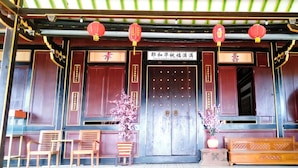 Um edifício tradicional chinês com porta de madeira, lanternas vermelhas e caracteres chineses.