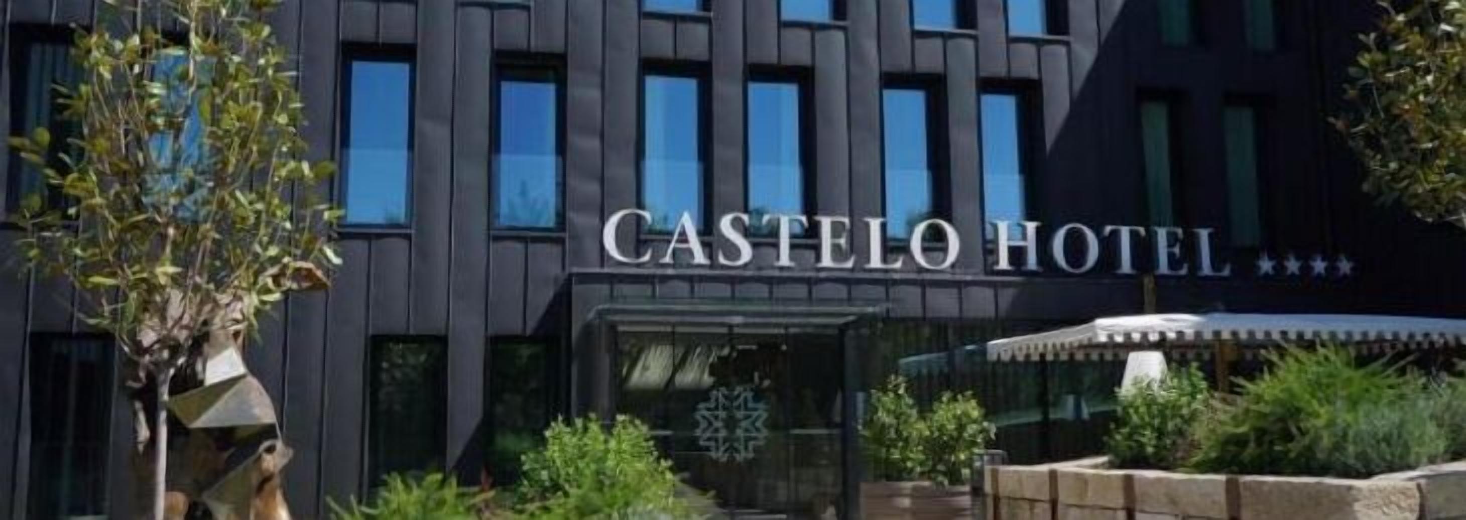 Exterior do Hotel Castello, com fachada moderna, grandes janelas e uma placa visível.