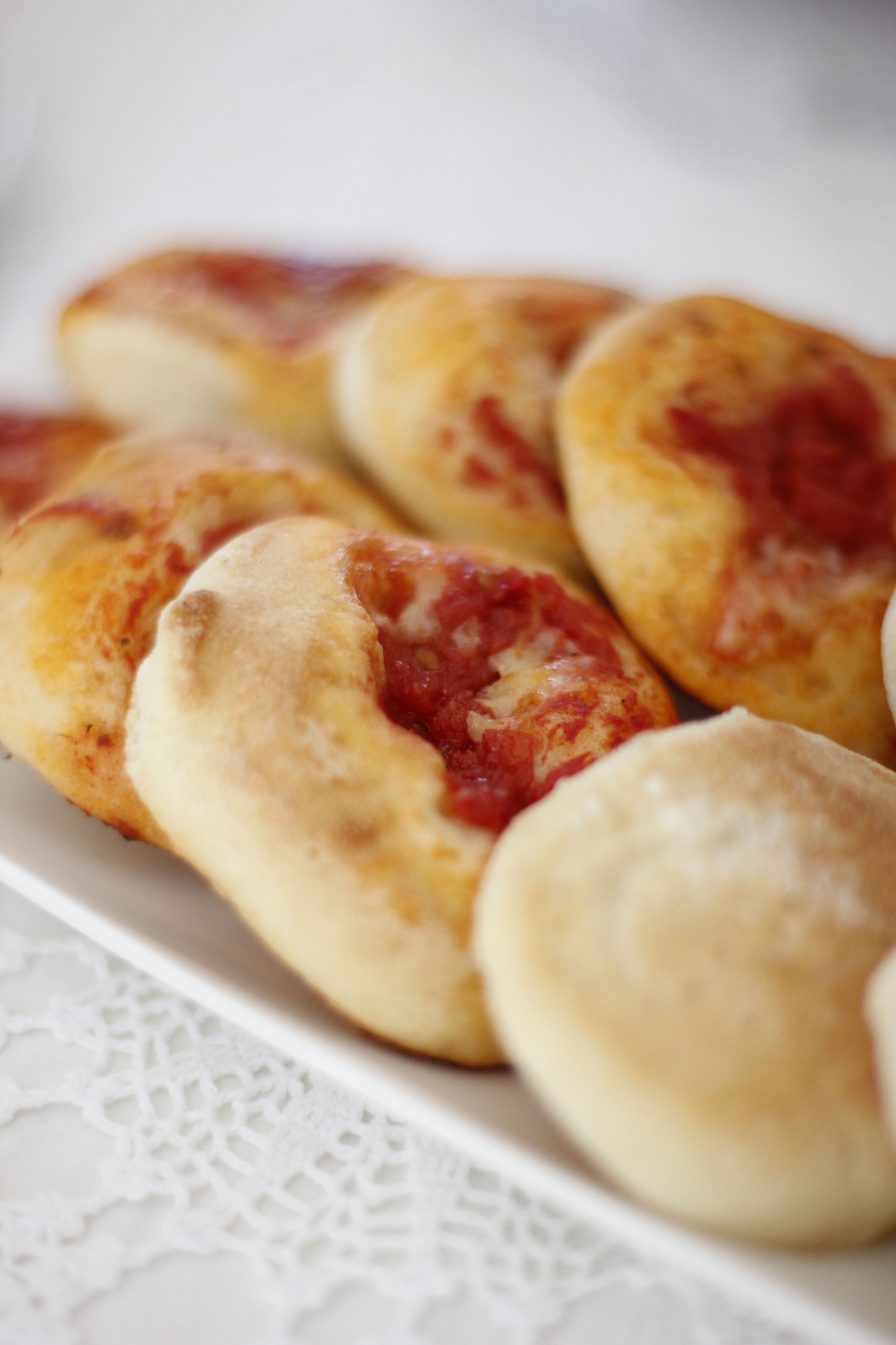 Um prato de pastelaria recheada com queijo sobre uma toalha de mesa branca.