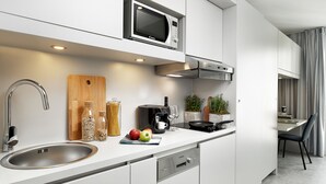 Uma cozinha moderna com micro-ondas embutido, pia de aço inoxidável e máquina de café.