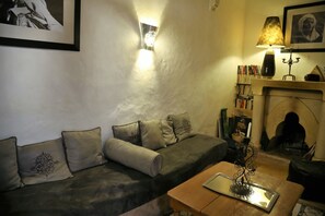 Uma sala de estar aconchegante com sofá, mesa de centro de madeira, estante de livros e lareira.