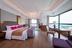 Quarto de hotel espaçoso com uma cama grande, uma escrivaninha e vista para a cidade.