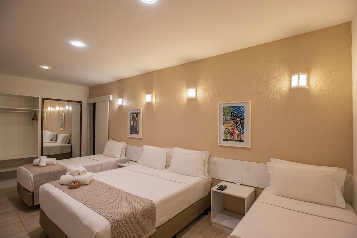 Quarto de hotel com duas camas, um closet espaçoso e banheiro com espelho.
