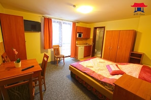 Quarto de hotel com cama, escrivaninha, cadeira, televisão, micro-ondas e guarda-roupa.