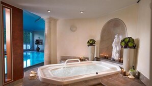 Uma área de spa com uma banheira de hidromassagem, um espelho grande e vista para uma piscina.