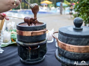 Uma configuração tradicional de panela de pedra quente, com uma faixa de cobre, um pouco de chocolate sendo mergulhado e uma panela tampada sobre uma mesa.