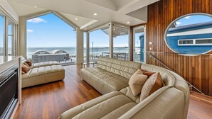 Uma sala de estar moderna com uma grande janela com vista para o oceano, uma parede de madeira e uma janela circular.
