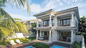 Uma casa de dois andares com piscina, área de estar externa e varanda.