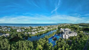 Um resort com vários edifícios, uma piscina grande e vista para o mar.
