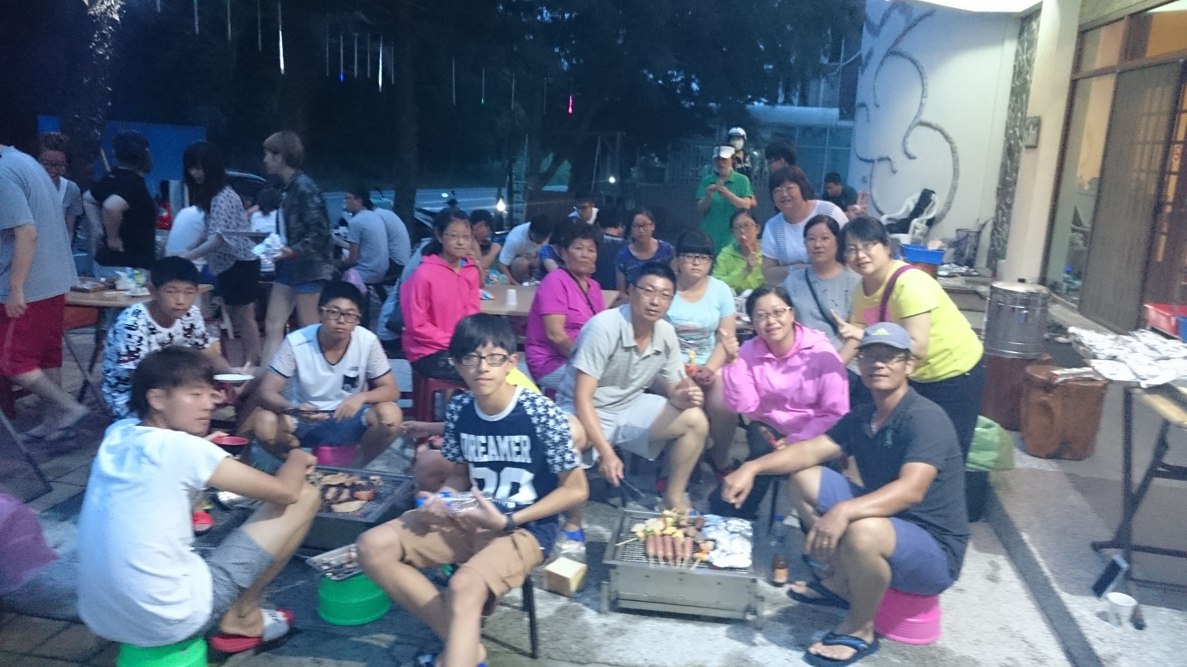 Um grupo de pessoas reunido em volta de uma churrasqueira ao ar livre.