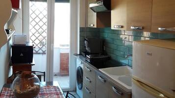 Um frigorífico, uma placa de cozinha, uma máquina de café expresso