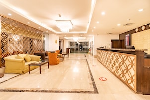Um hall de hotel com balcão de recepção, área de estar e um painel decorativo.