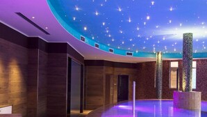 Uma área de piscina interna moderna com teto estrelado, paredes de madeira e um elemento aquático central.