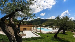 Área de piscina com espreguiçadeiras e um edifício ao fundo.