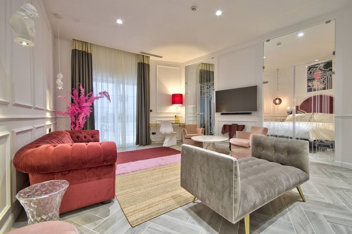 Uma sala de estar moderna com um sofá vermelho, uma poltrona cinza e uma mesa de centro de vidro.