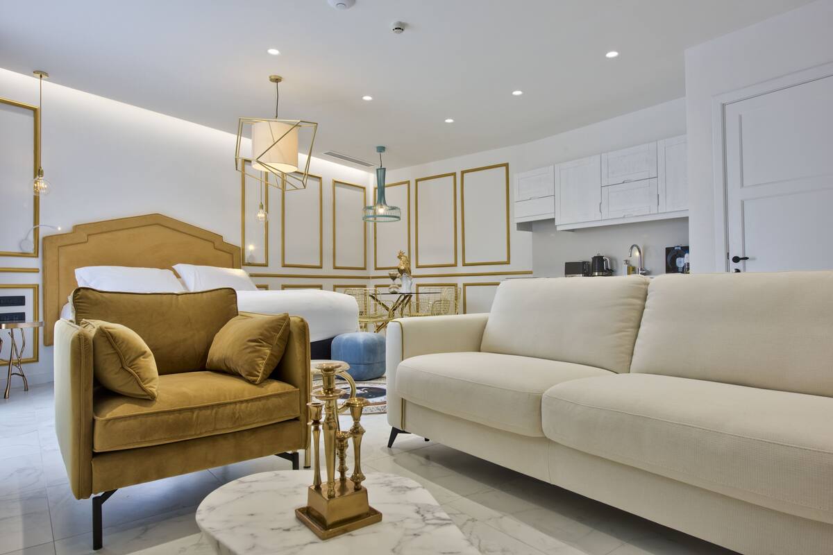 Uma sala de estar moderna com uma cama grande, dois sofás e uma mesa de centro de mármore.