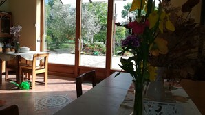 Uma sala de jantar com uma mesa, cadeiras e um vaso de flores.