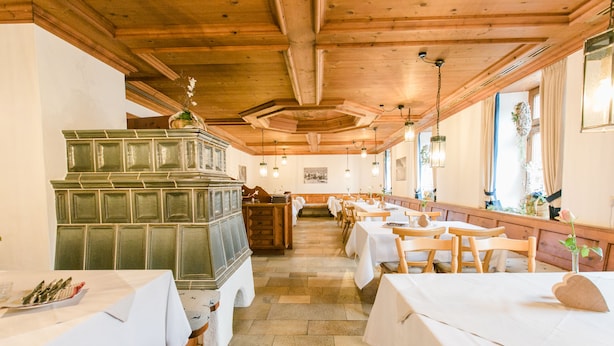 Restaurante com vigas de madeira, mesas brancas e uma lareira central.